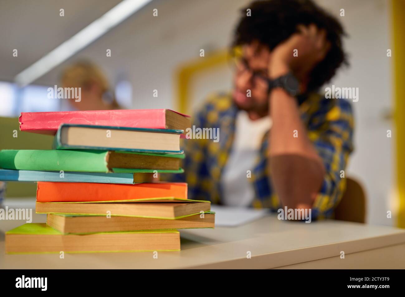 A lot of books in front of male student at the university classroom ...