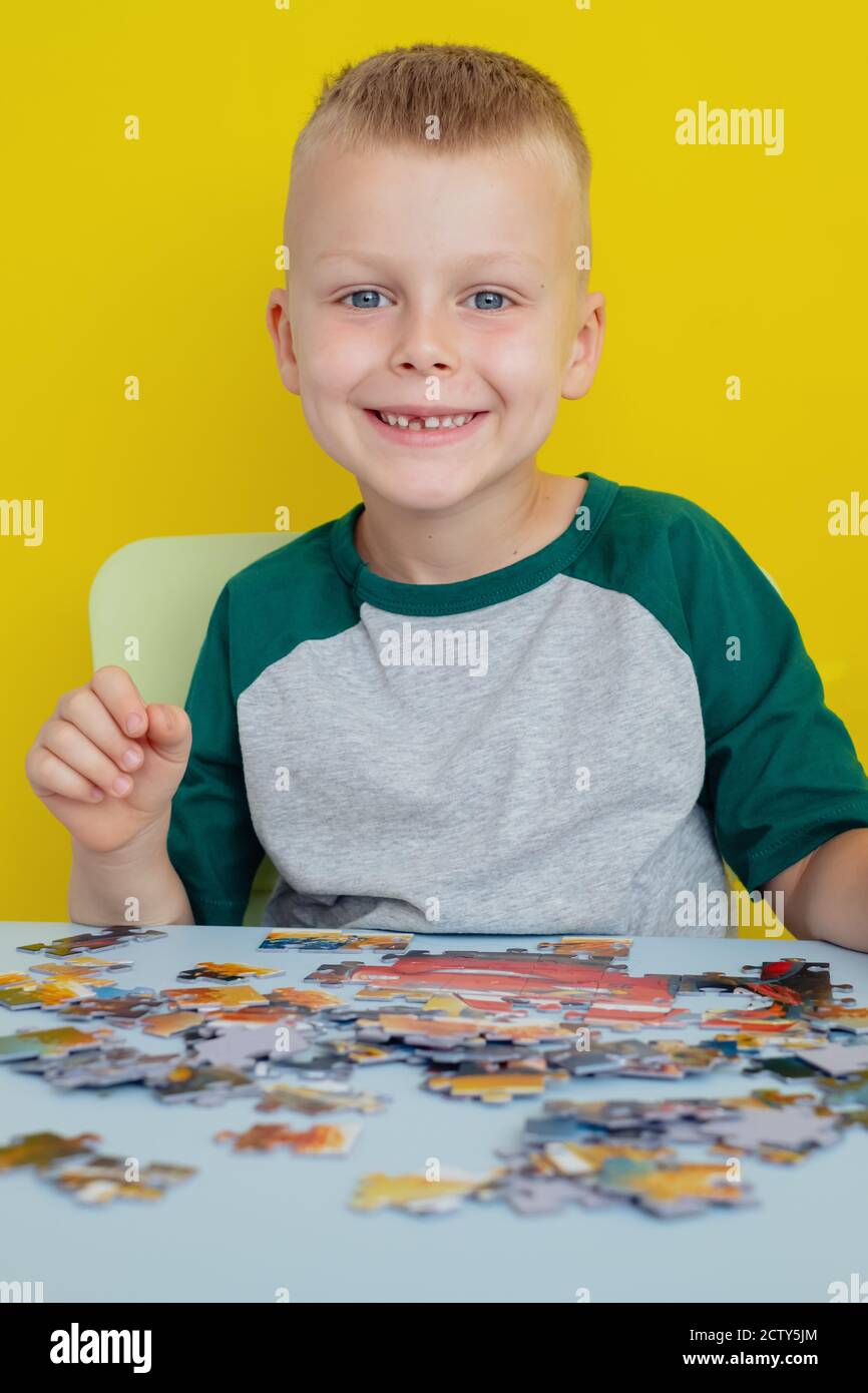 kid sitting at the table and putting together puzzles. Early learning ...