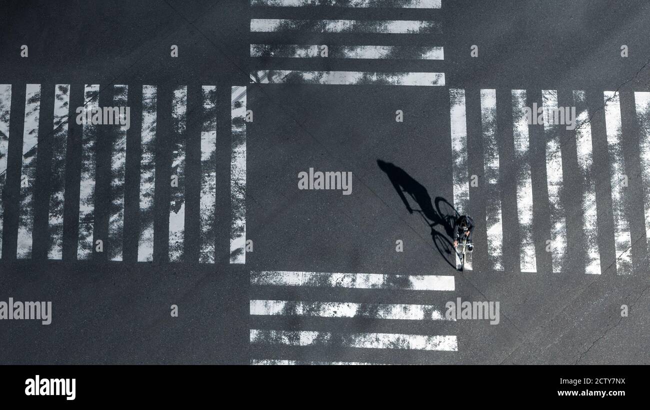 Elevated view over a biker man on pedestrian crossing in road ...