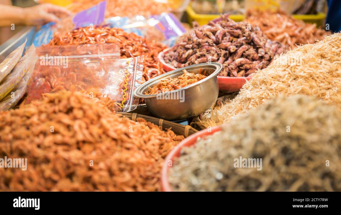 A stall vendor selling dry shrimp fish and various ingredients in a ...