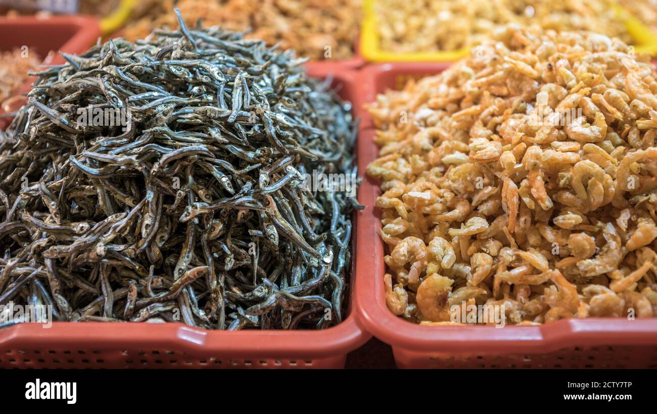 A stall vendor selling dry shrimp fish and various ingredients in a ...