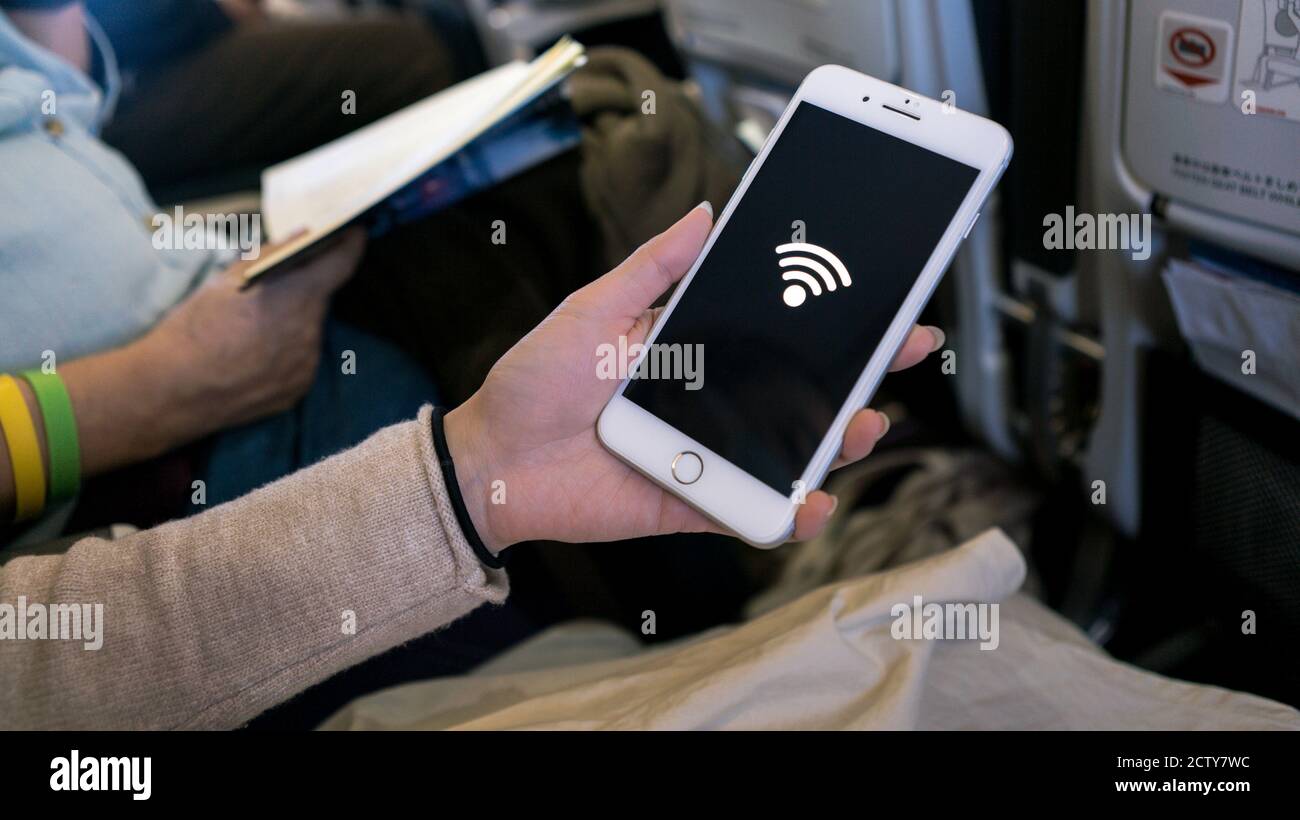 Asian woman holding the smartphone during flight trip. Traveller sit ...