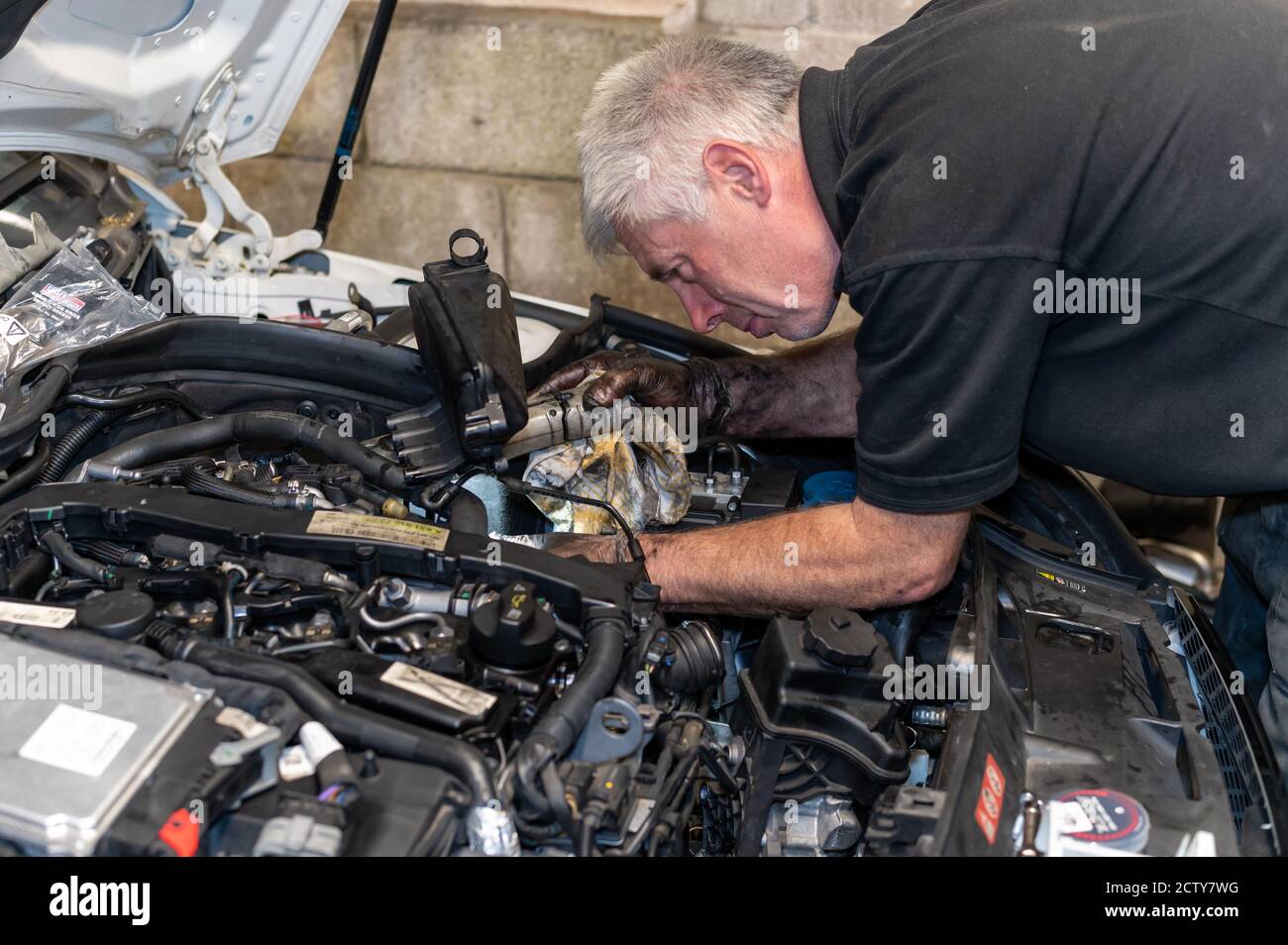 Senior Mechanic working on engine bay repairing a oil leak in home ...