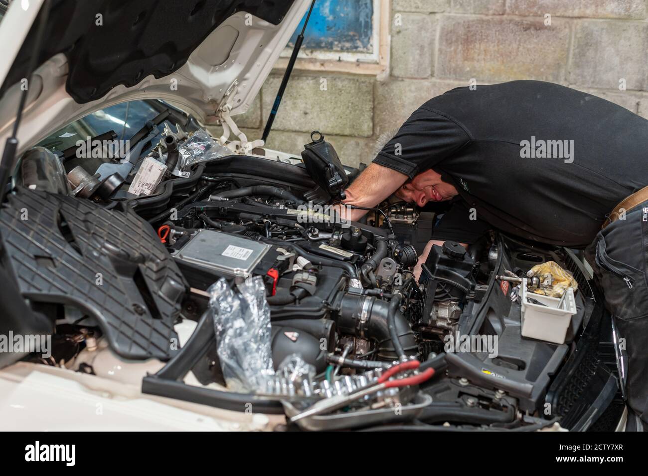 Senior Mechanic working on engine bay repairing a oil leak in home ...