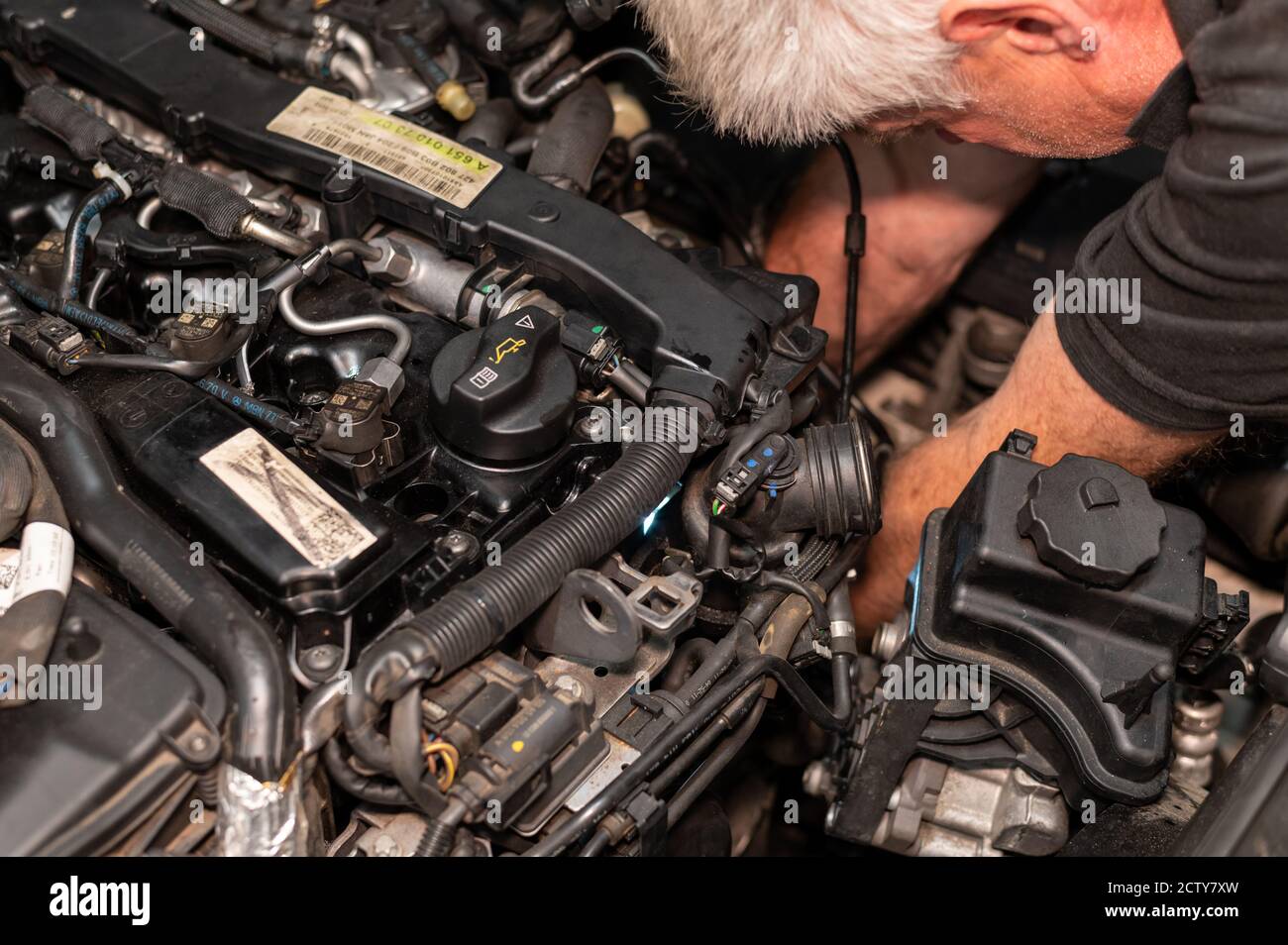 Senior Mechanic working on engine bay repairing a oil leak in home ...