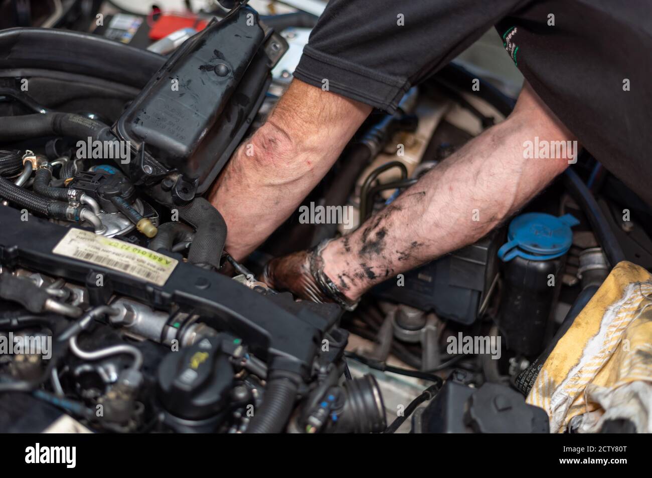 Senior Mechanic working on engine bay repairing a oil leak in home ...