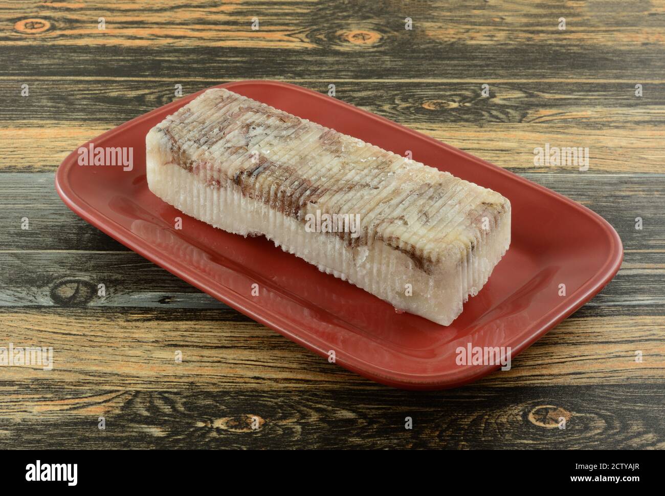 Frozen block of squid tubes and tentacles thawing on red platter Stock ...