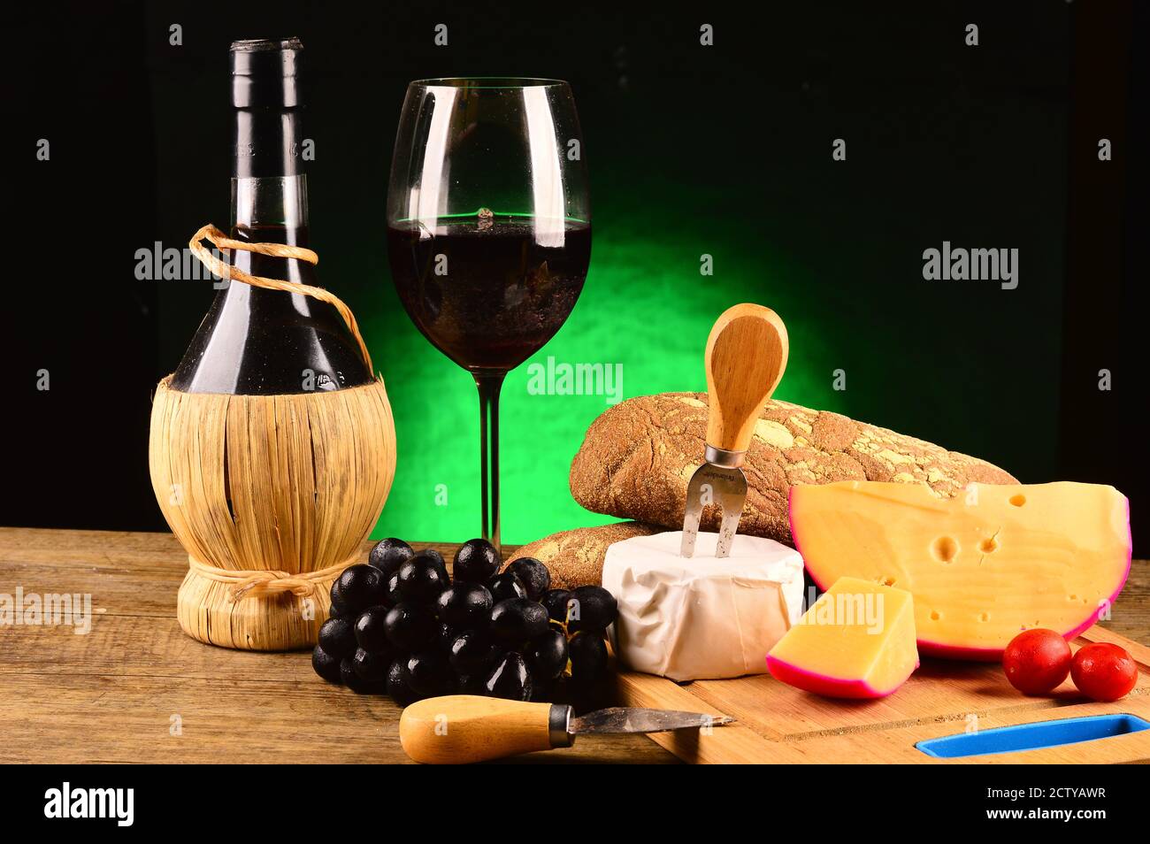 Glass and bottle of red wine with cheese, bread and a wooden barrel ...