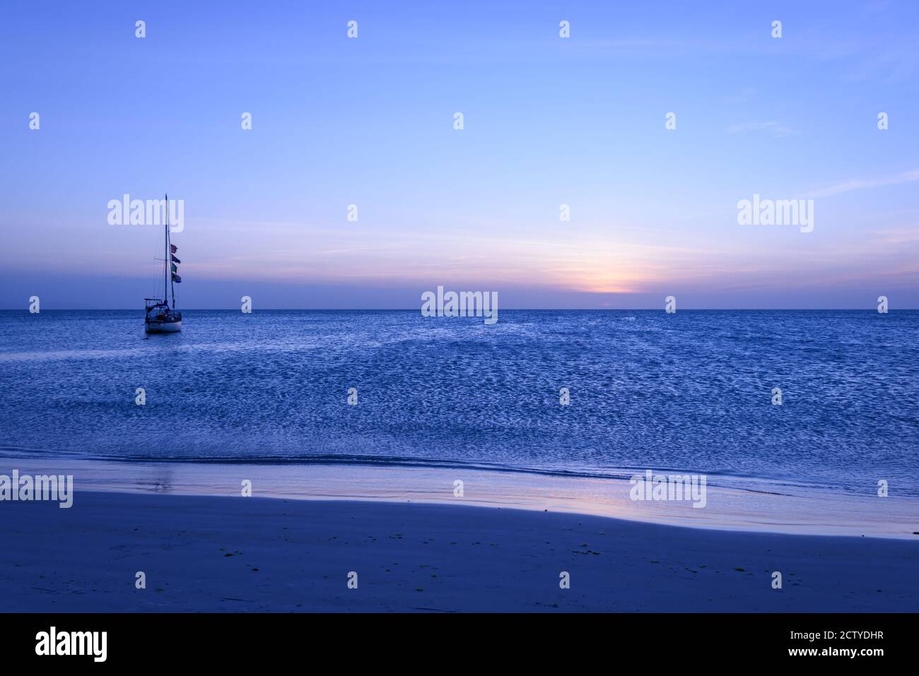 Tropical white beach in Coche island during sunset with a sailing ship ...