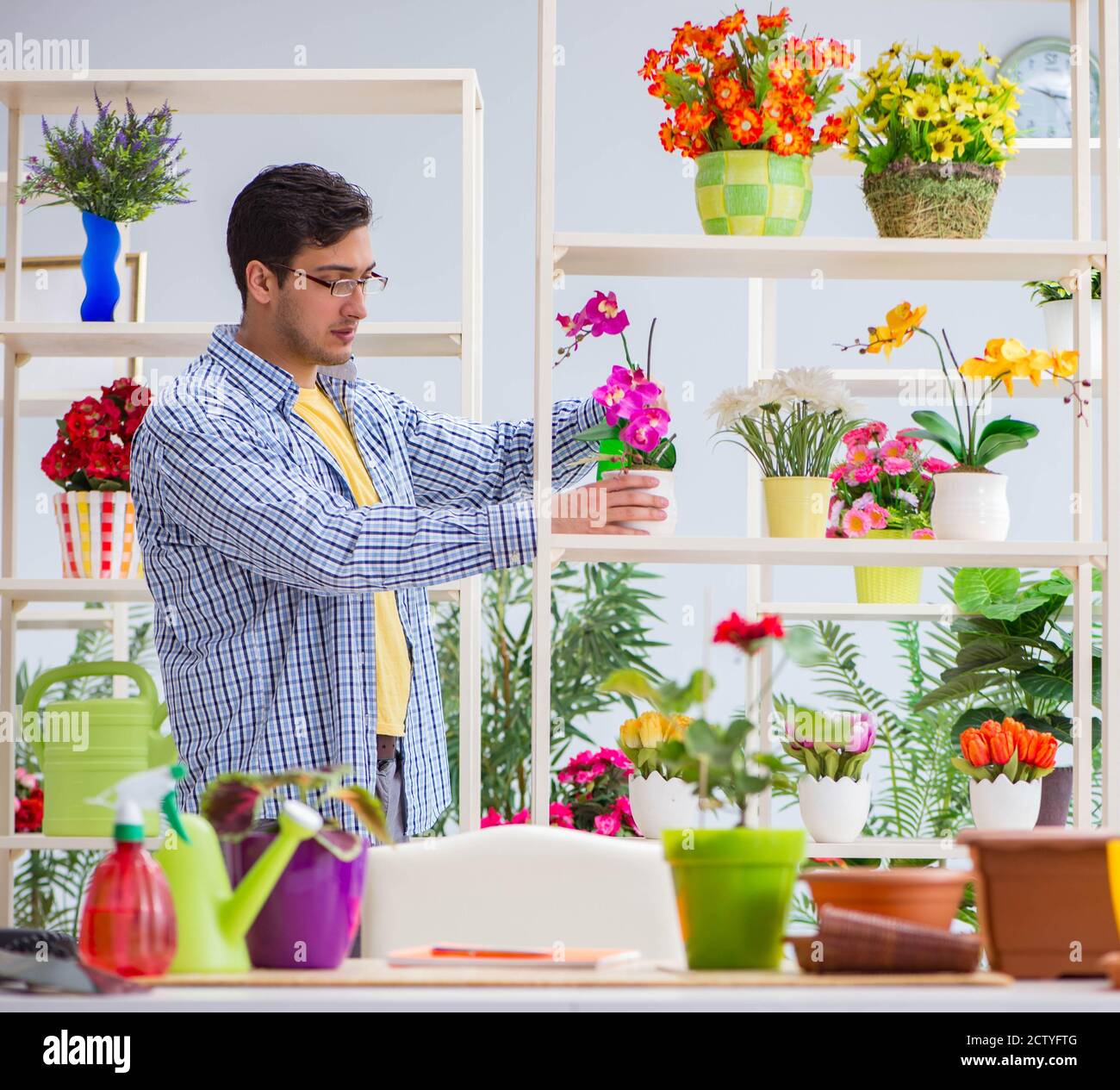 The young man florist working in a flower shop Stock Photo - Alamy
