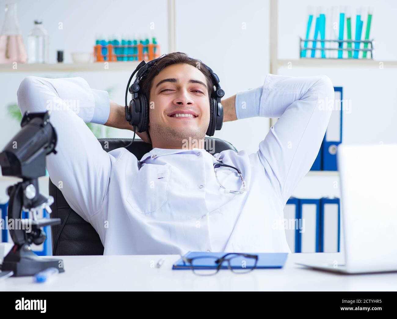 Happy excited doctor listening to music during lunch break in hospital ...