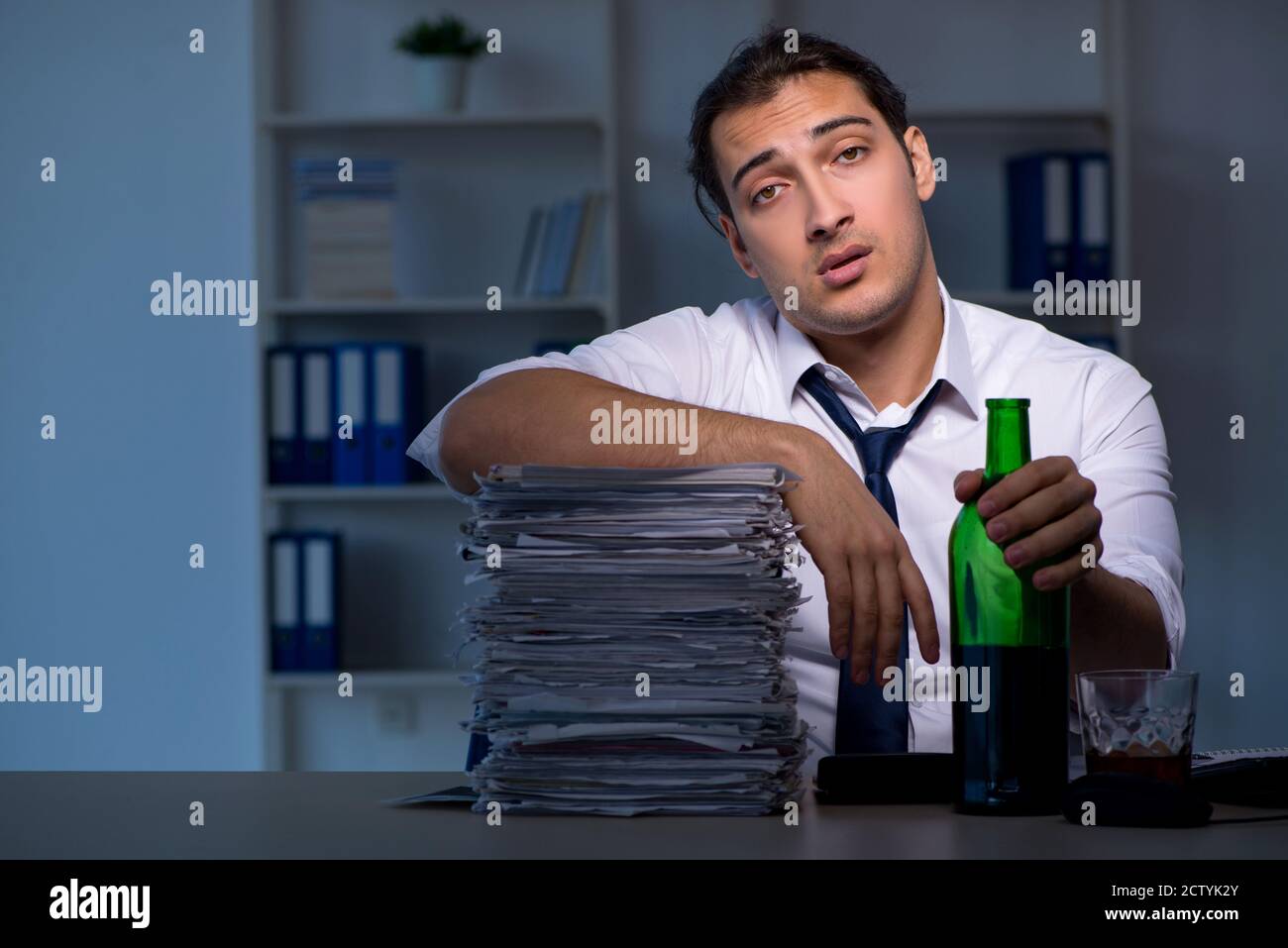Alcohol addicted businessman working late Stock Photo - Alamy