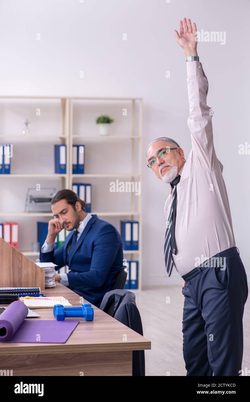Two employees doing physical exercises at the workplace Stock Photo - Alamy