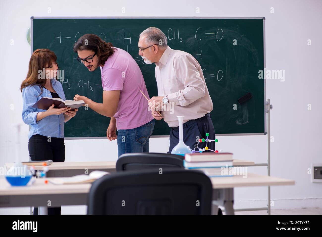 Old teacher and two students in the classroom Stock Photo - Alamy