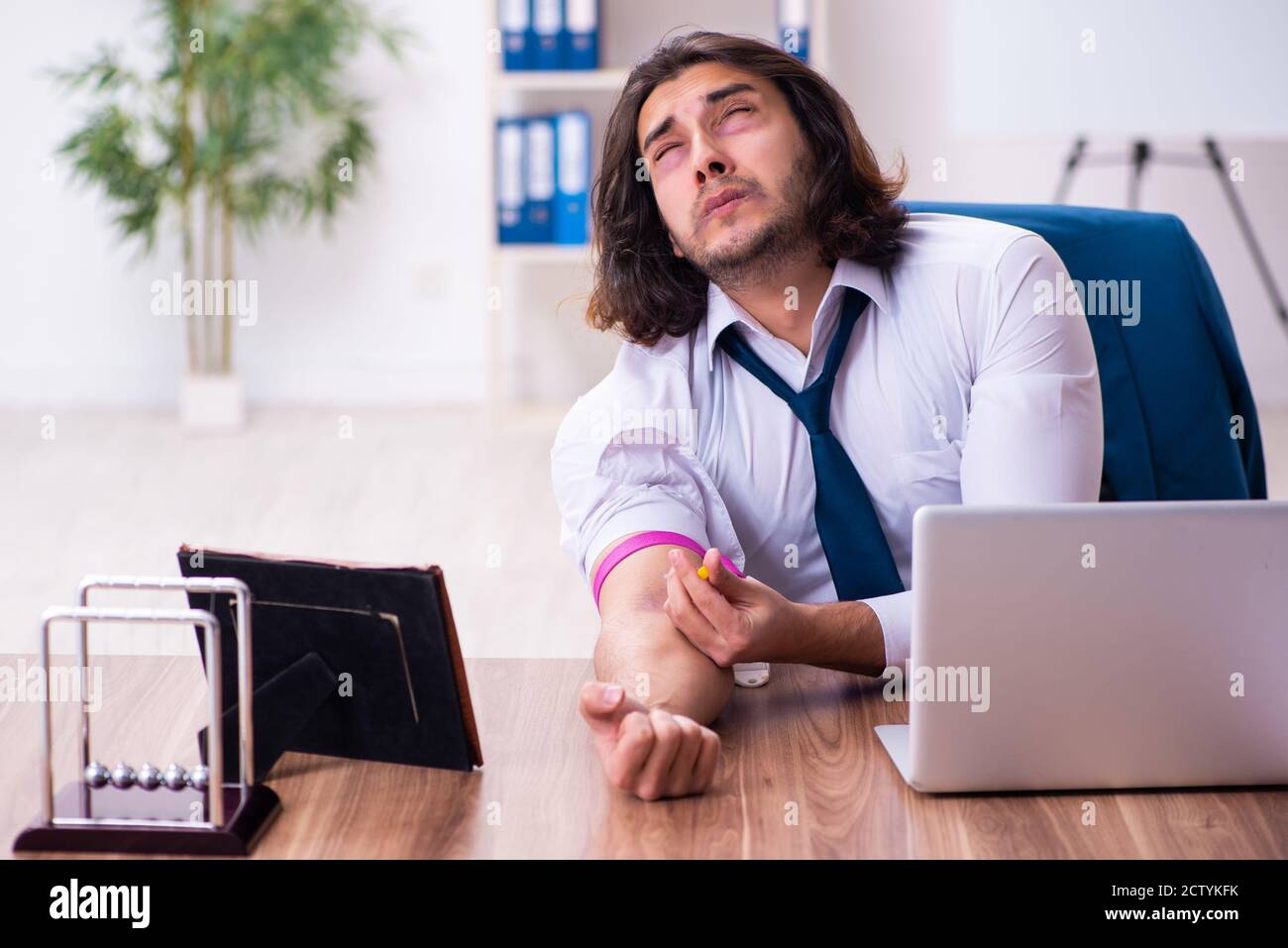 Drug addicted employee working in the office Stock Photo - Alamy