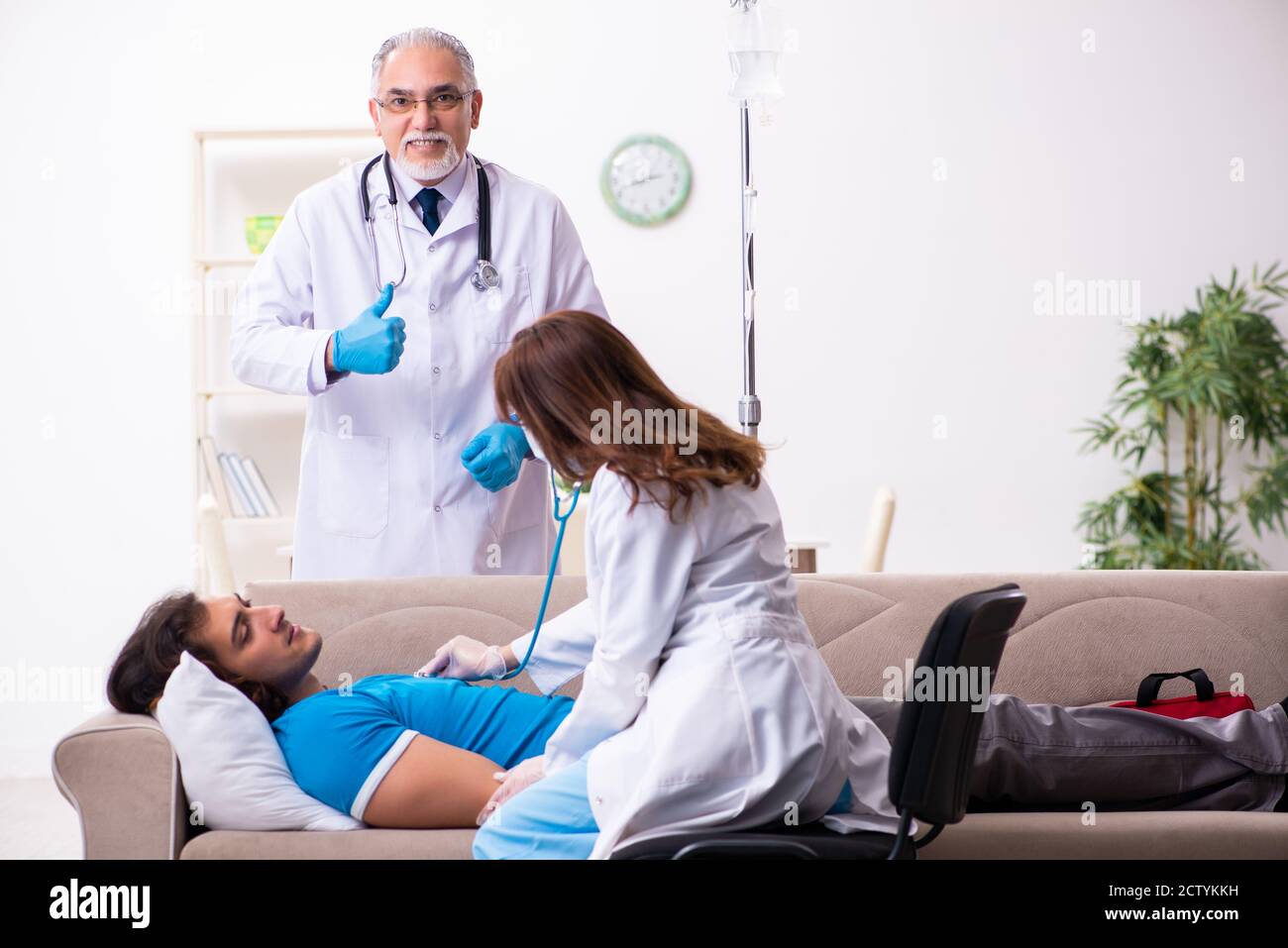 Two doctors visiting sick man at home Stock Photo - Alamy