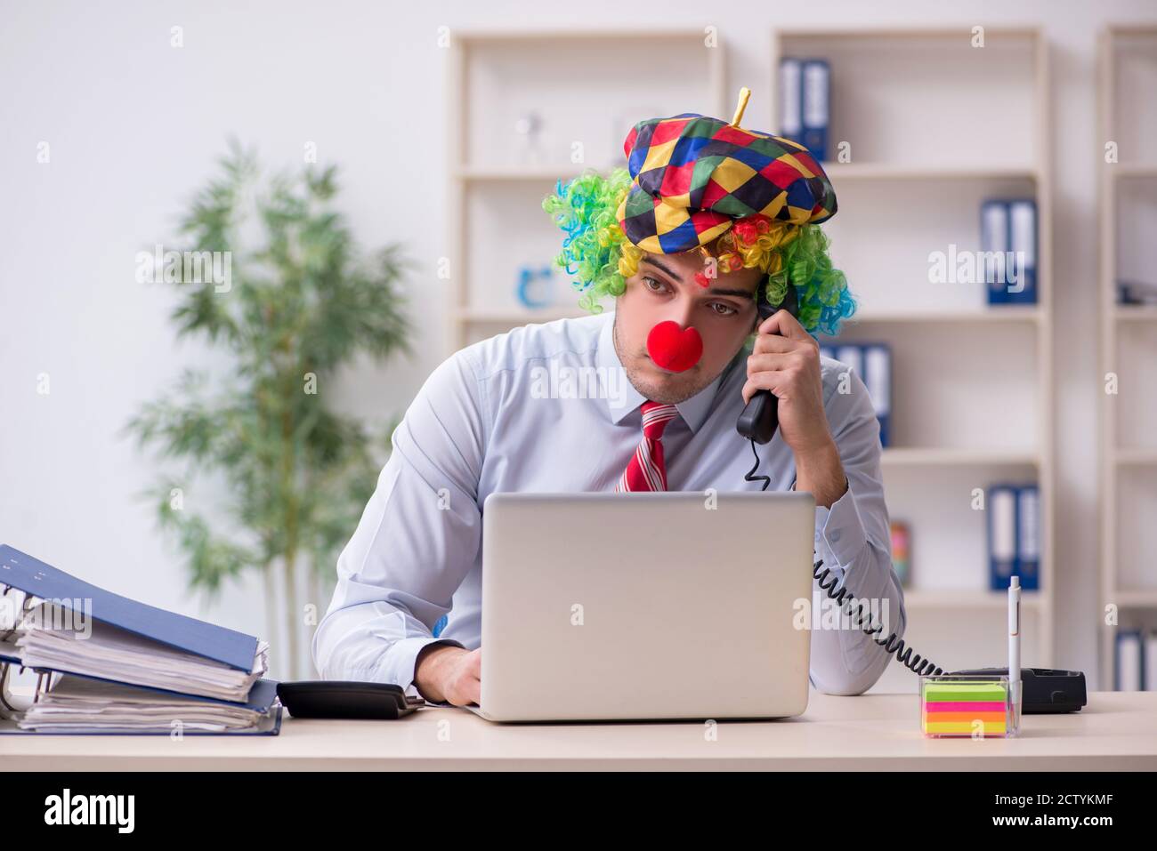 Funny employee clown working in the office room Stock Photo - Alamy
