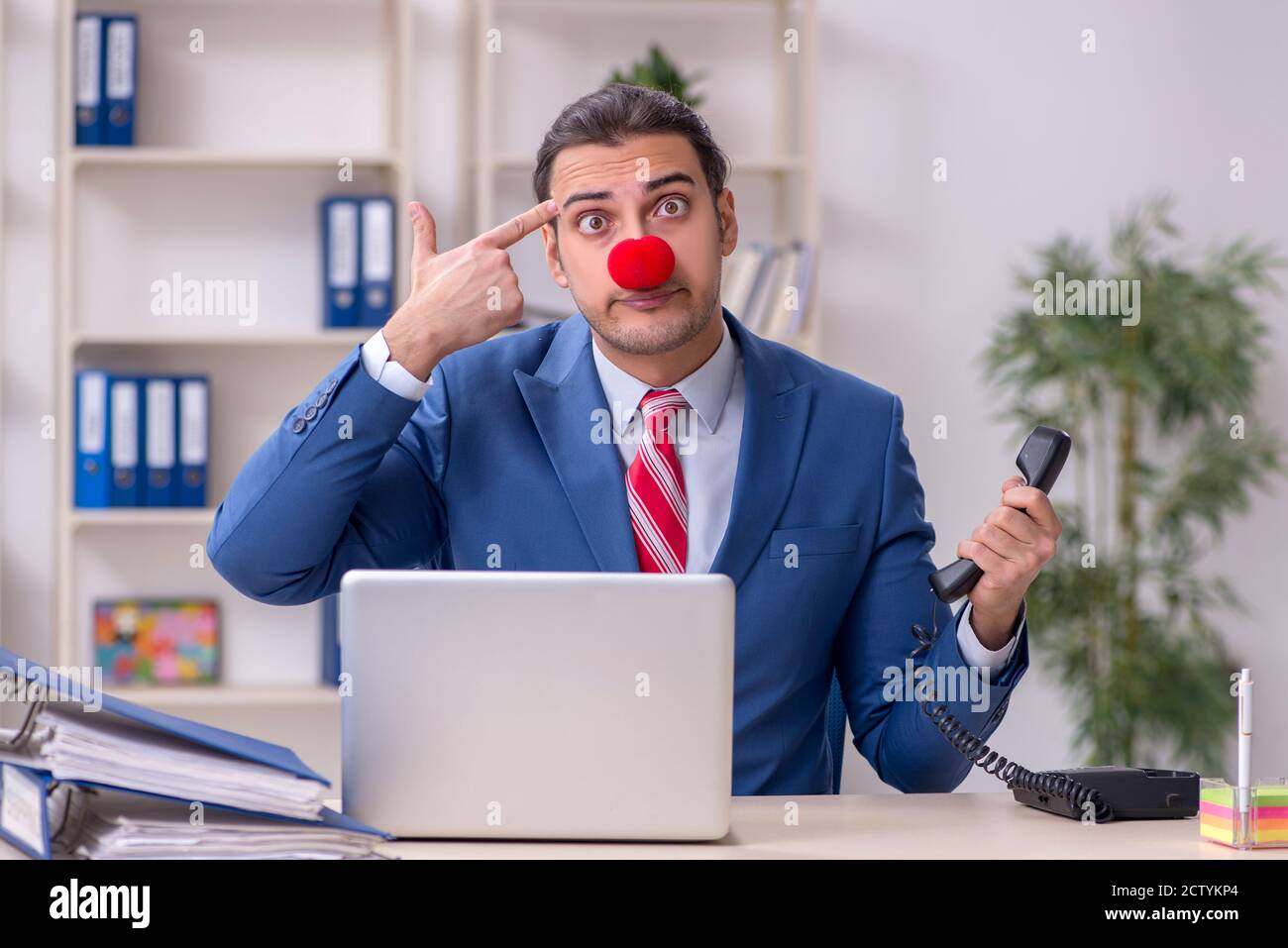 Funny employee clown working in the office room Stock Photo - Alamy