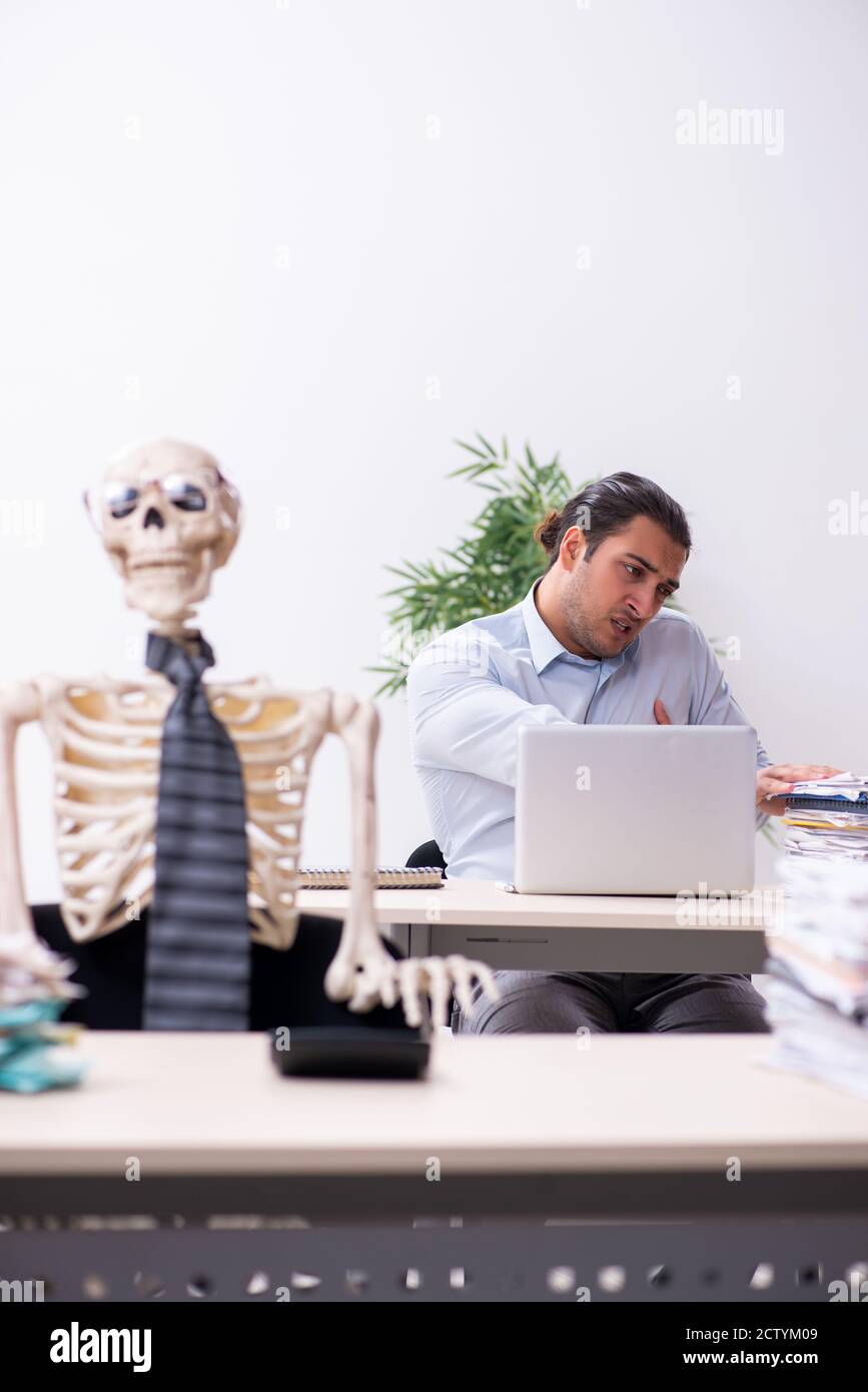Young employee and skeleton in the office Stock Photo - Alamy
