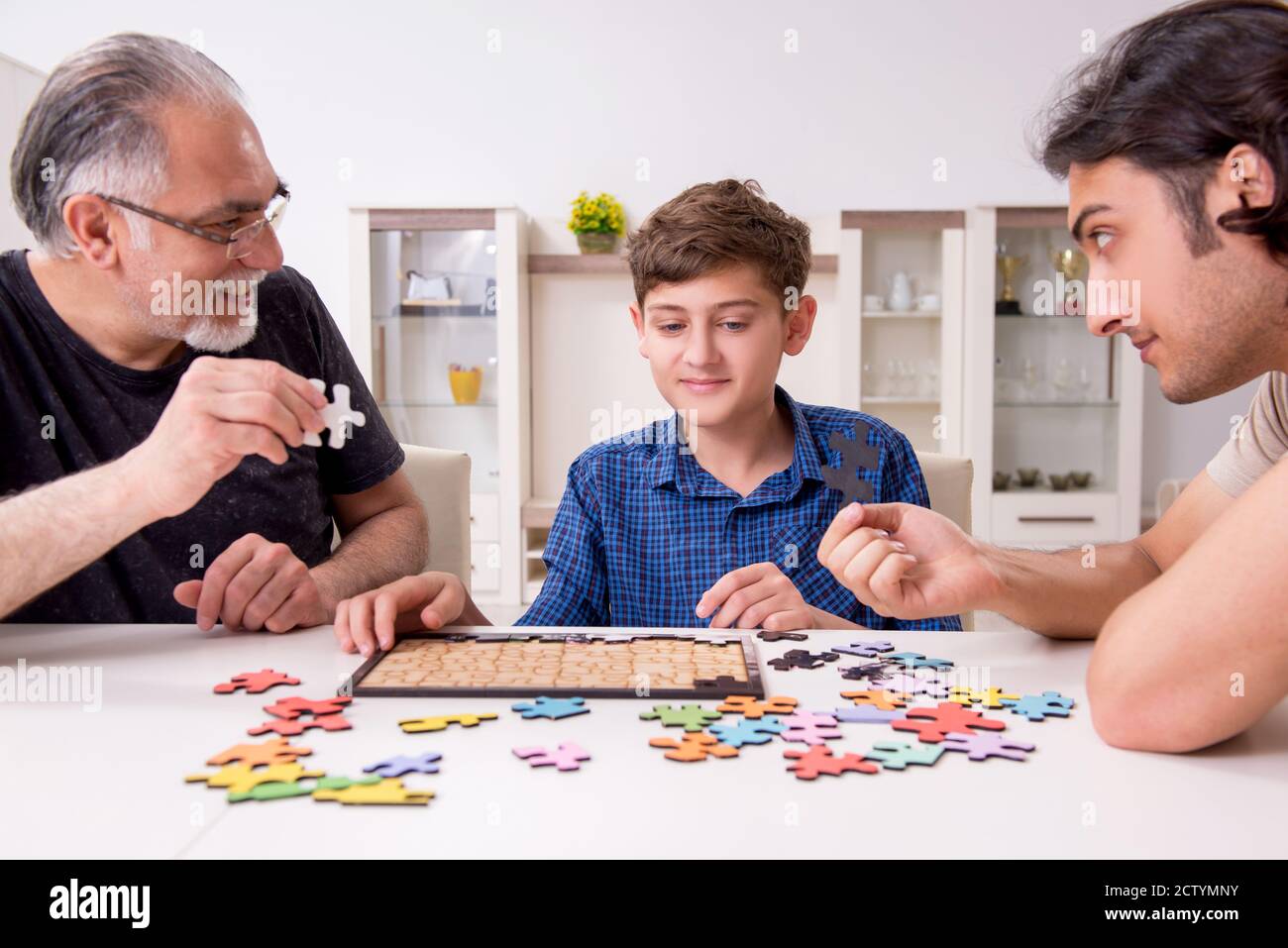 Three generations of family playing jigsaw puzzle Stock Photo - Alamy