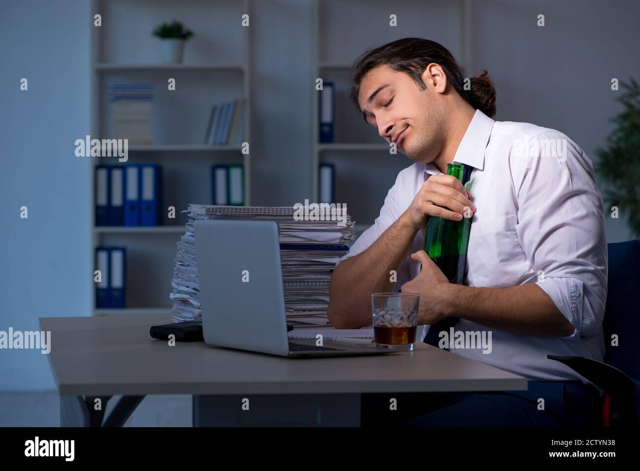 Alcohol addicted businessman working late Stock Photo - Alamy
