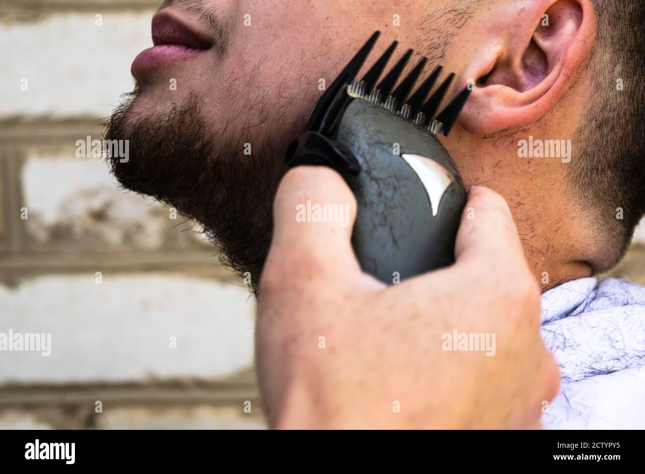 the barber cuts his beard to the guy with a shearing machine Stock ...