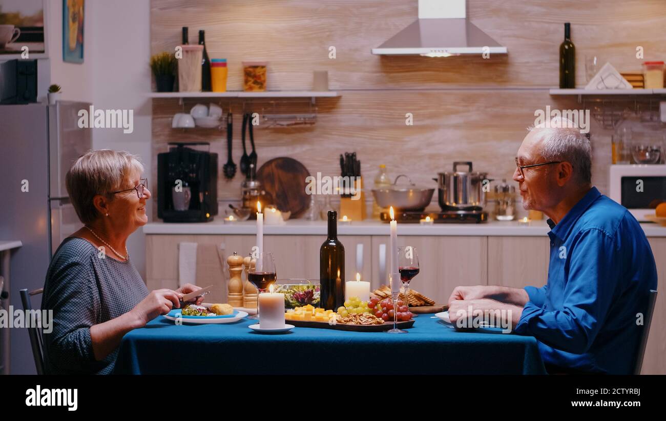 Senior couple relax eating dinner and drinking wine glasses together in ...
