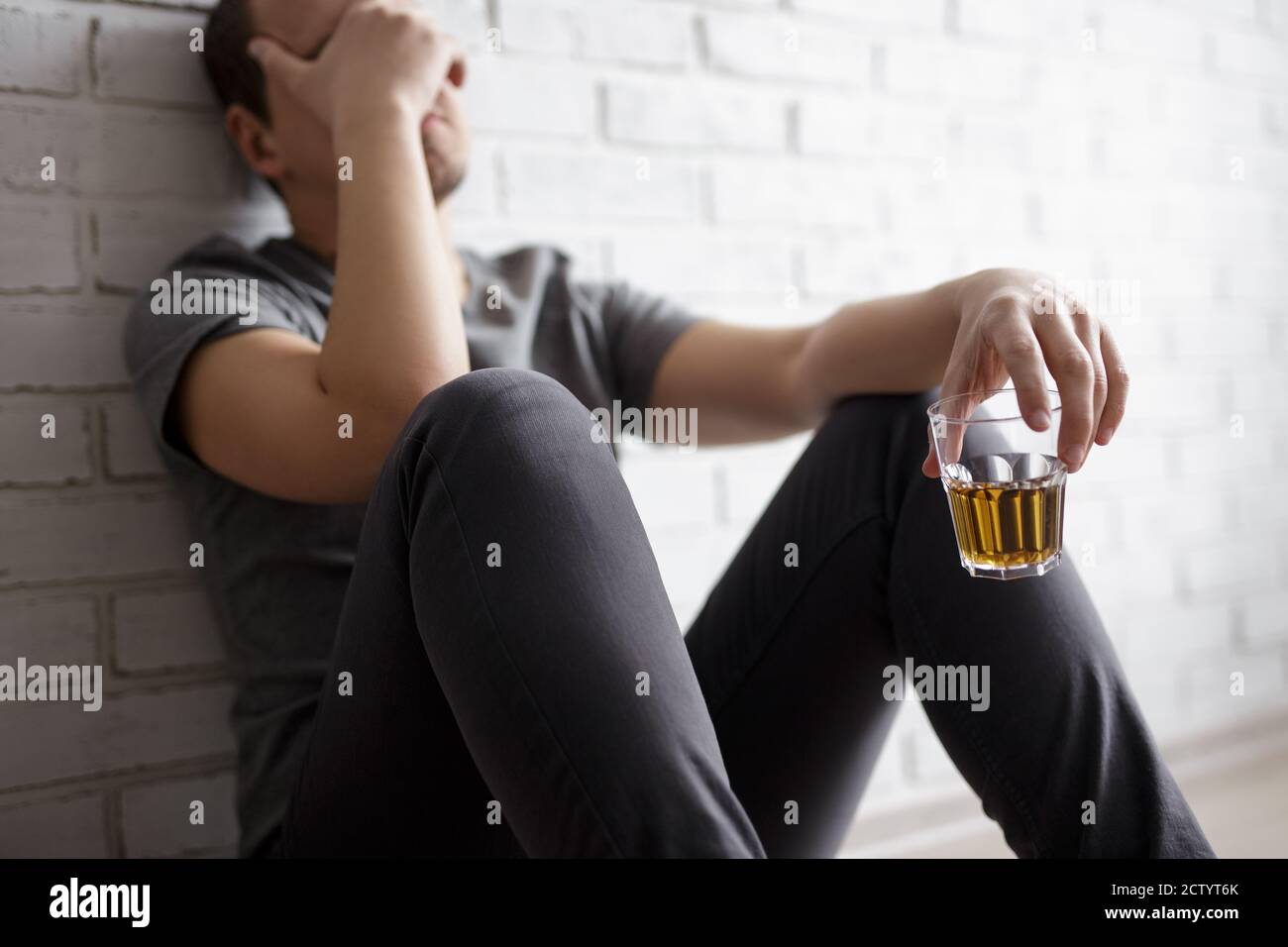 young man suffering from alcoholism, guy sitting with glass of whiskey ...