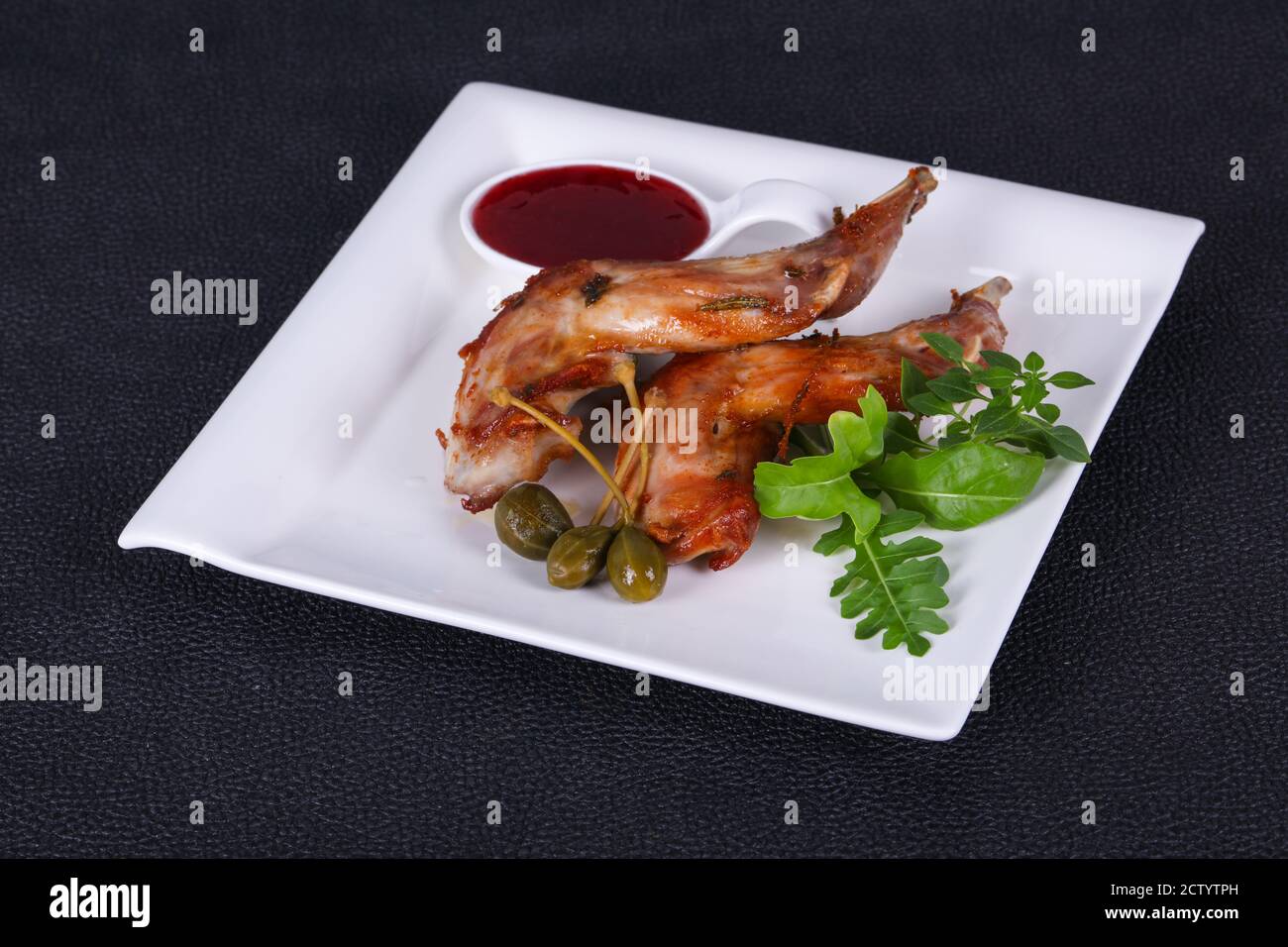 Roasted rabbit legs with cowberry sauce Stock Photo - Alamy