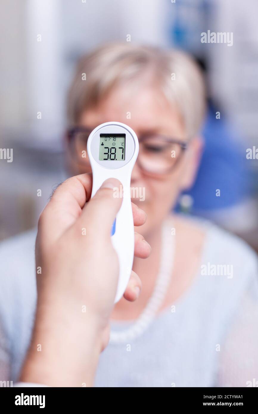 Senior patient having high temperature measured using infrared ...