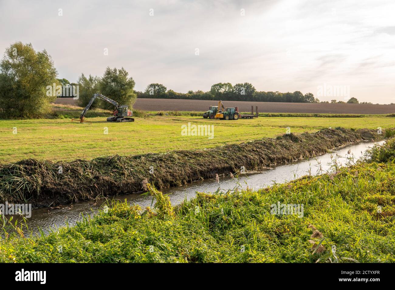 on a meadow there are tractors and excavators to dig a water ditch ...