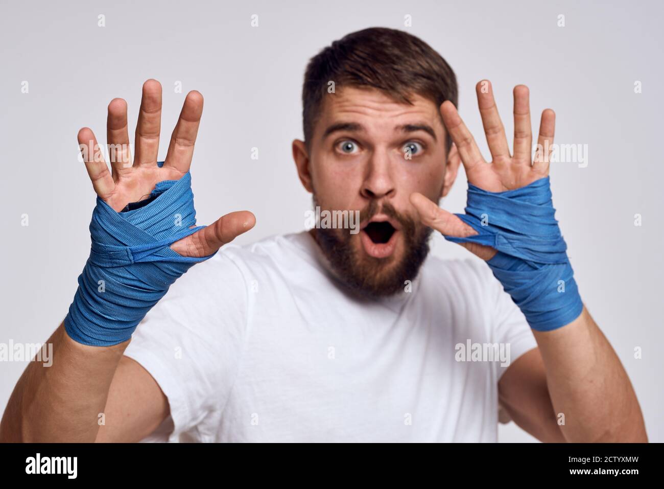 A sportive man in a white T-shirt boxing bandages on his hands ...