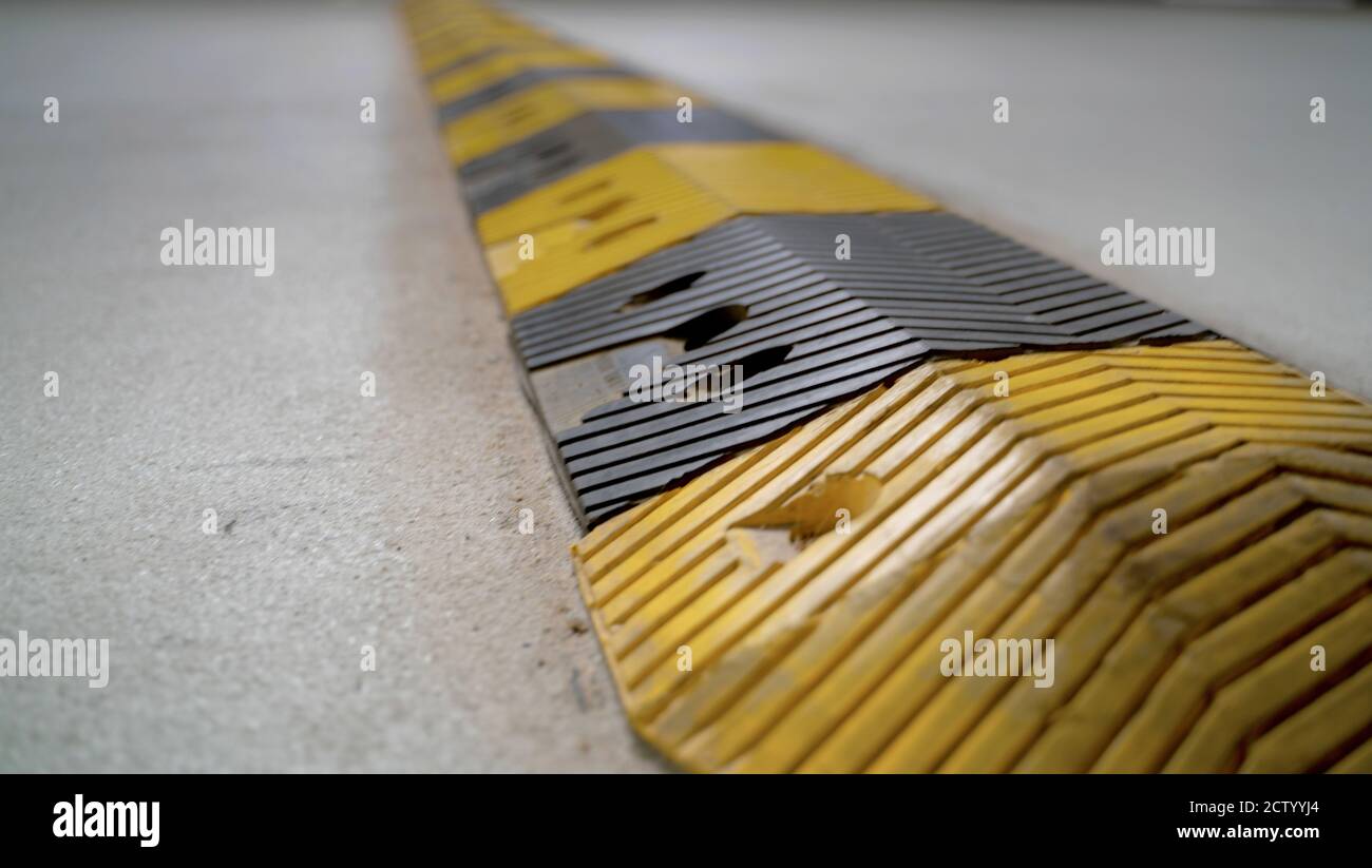Traffic safety speed bump on an asphalt road in a parking area. Speed ...