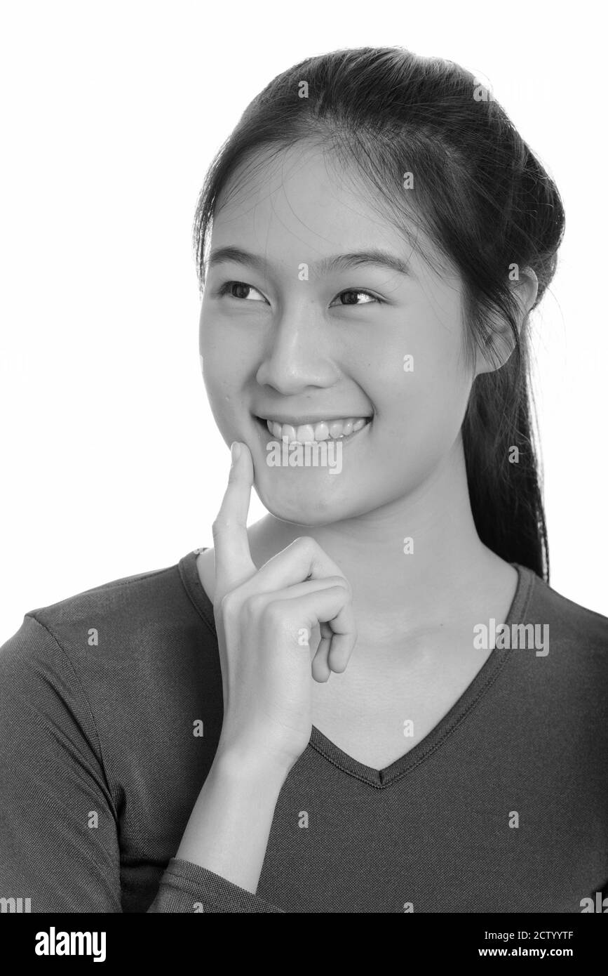 Young happy Asian teenage girl smiling and thinking Stock Photo - Alamy