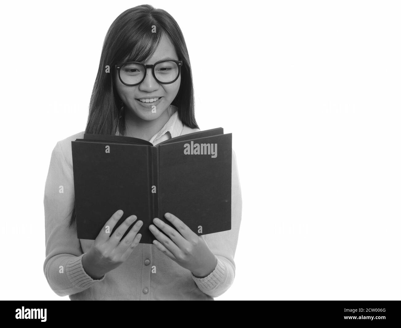 Young happy Asian teenage girl smiling and reading book Stock Photo - Alamy