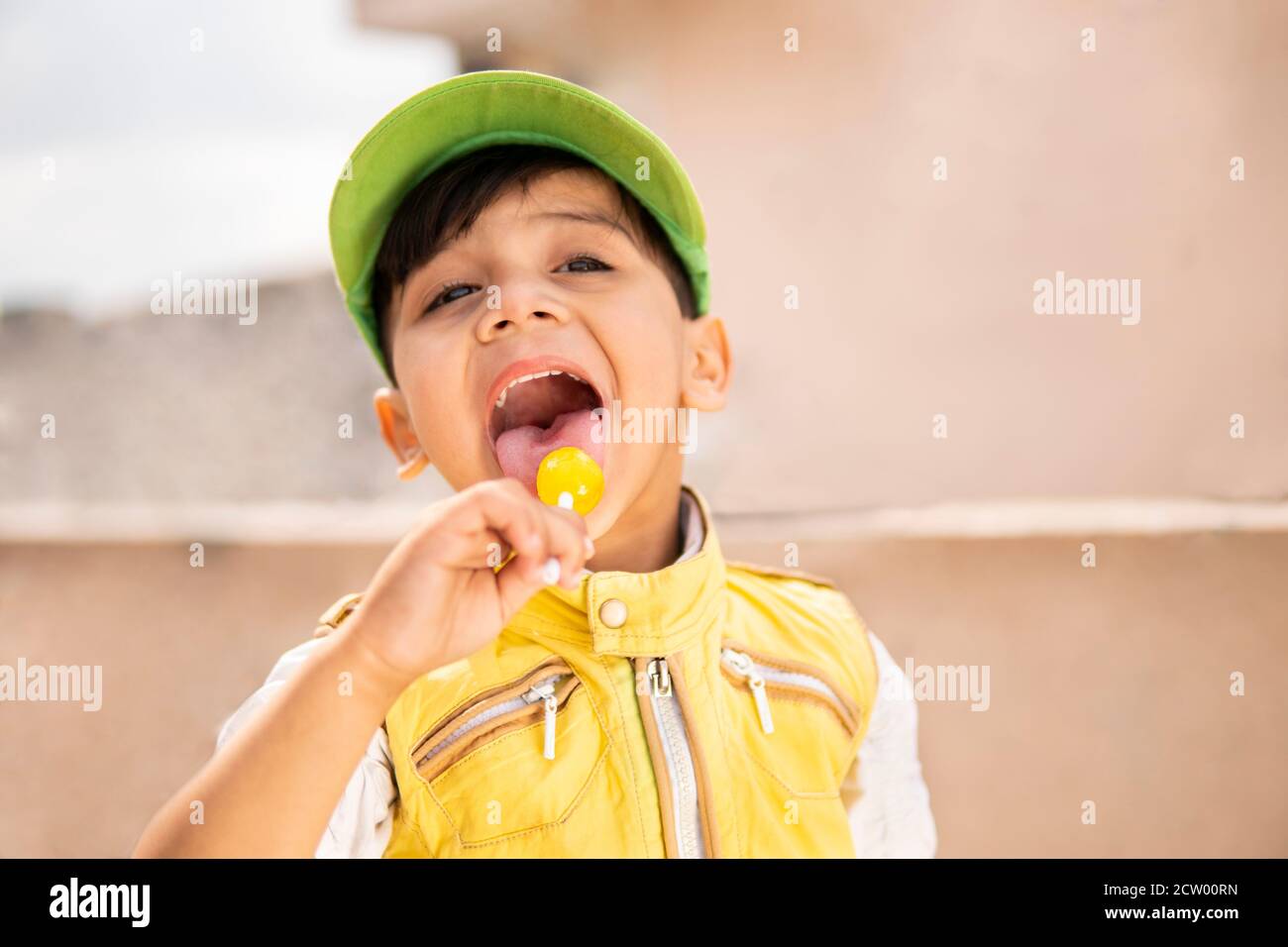 Cut little boy eating lollipop candy and having fun in outdoor at day ...