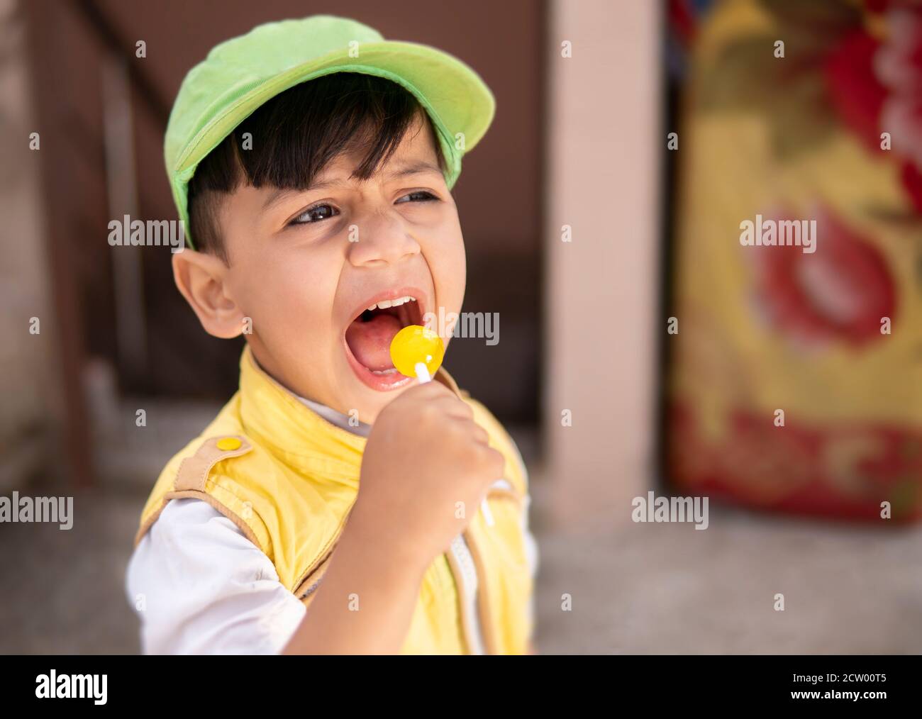 Cut little boy eating lollipop candy and having fun in outdoor at day ...