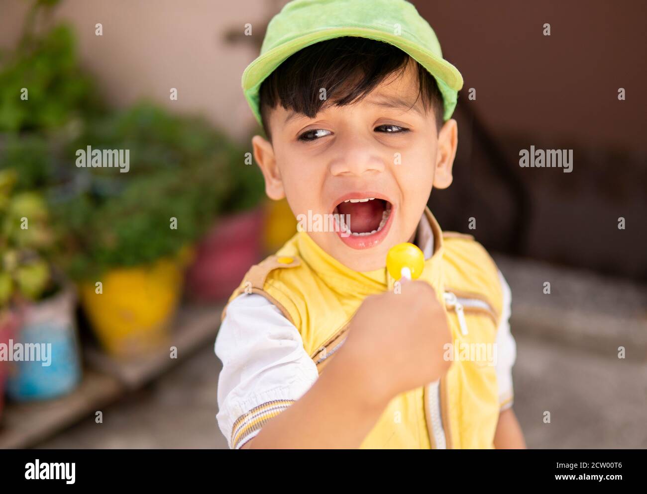 Cut little boy eating lollipop candy and having fun in outdoor at day ...