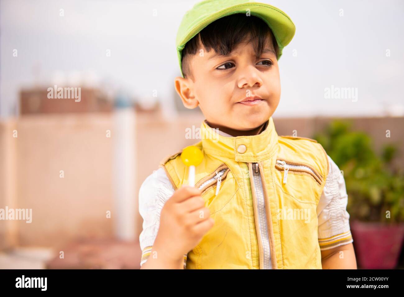Cut little boy eating lollipop candy and having fun in outdoor at day ...