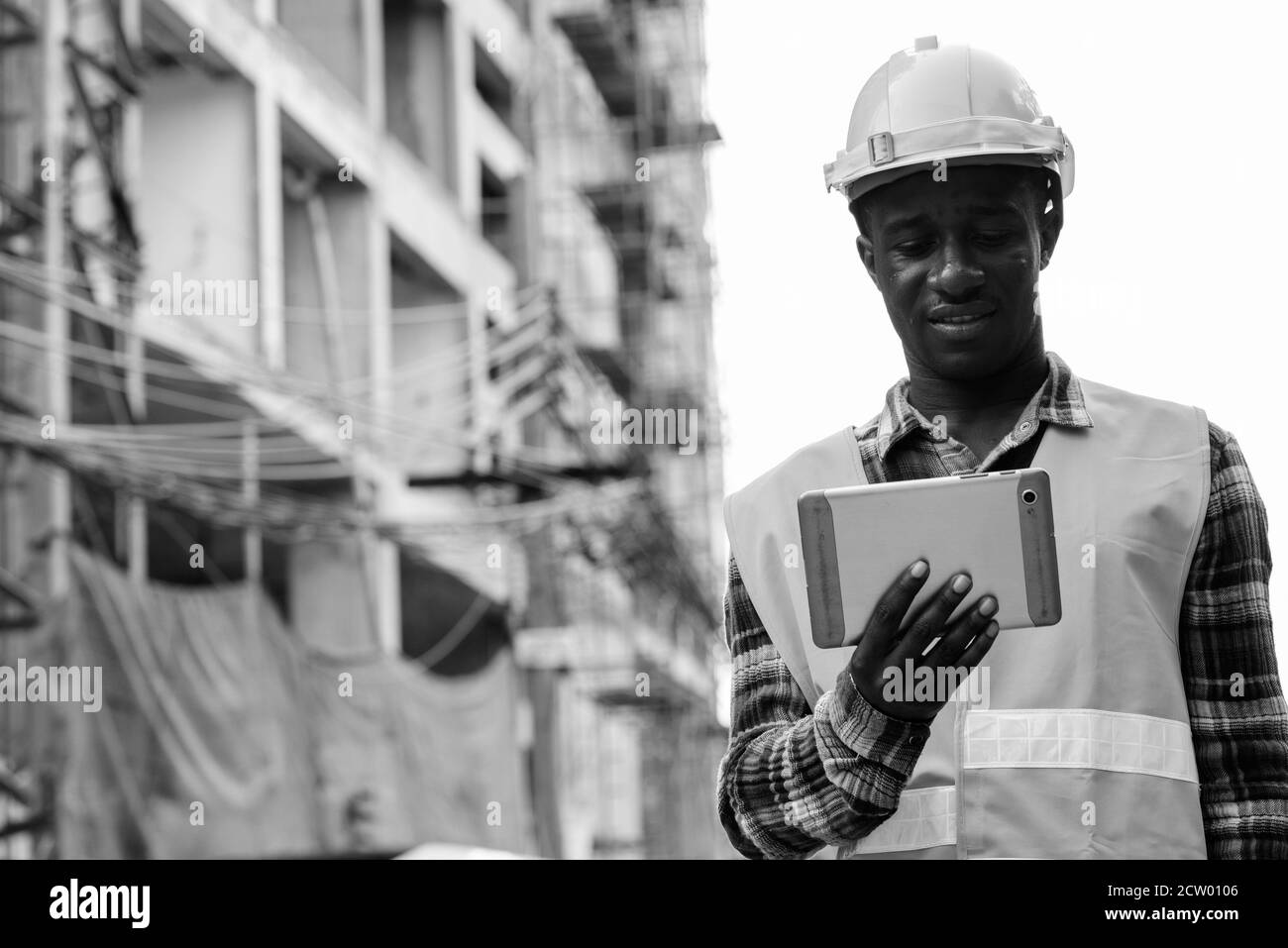 Young happy black African man construction worker smiling while using ...