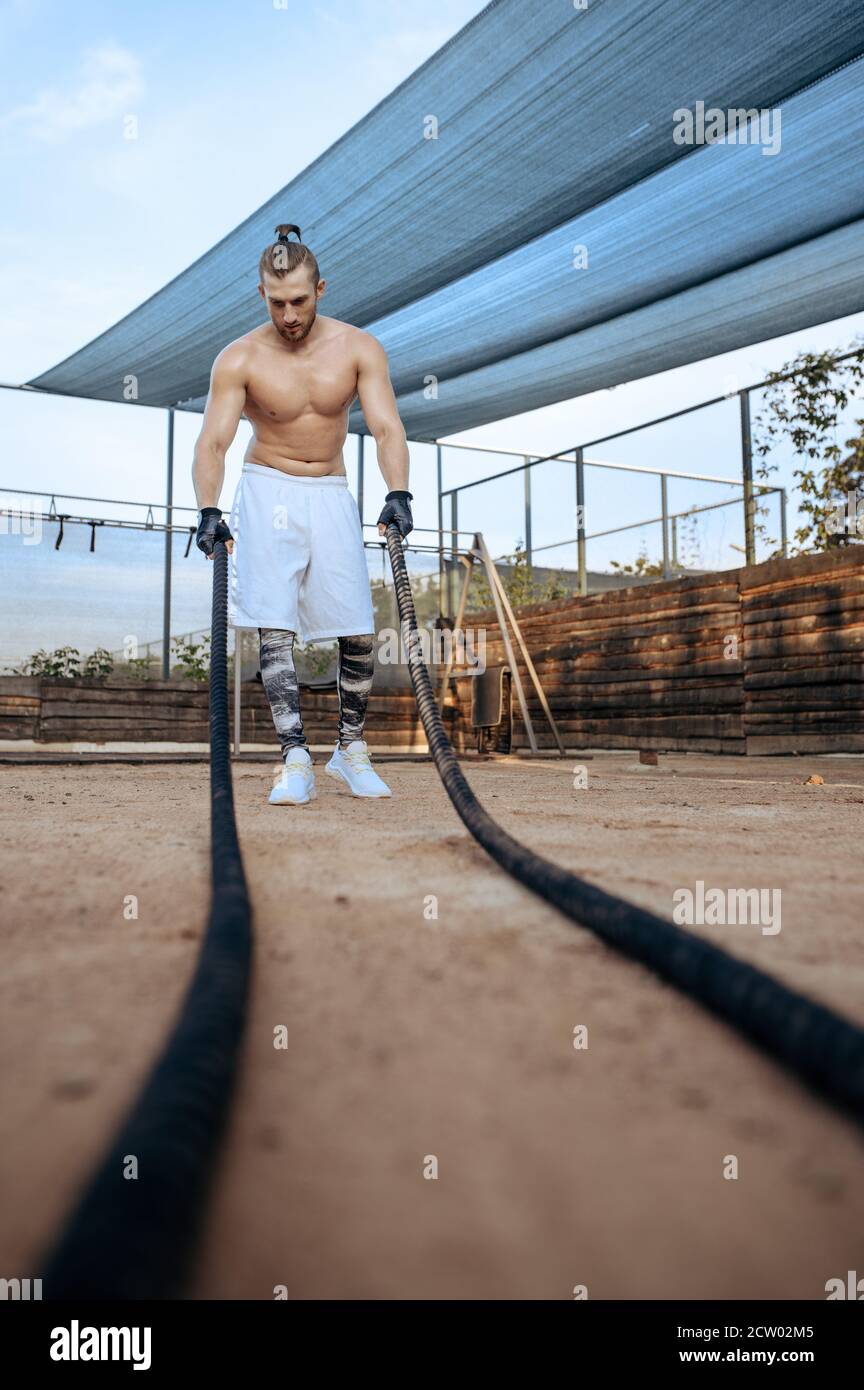 Muscular man doing exercise with ropes, crossfit Stock Photo - Alamy