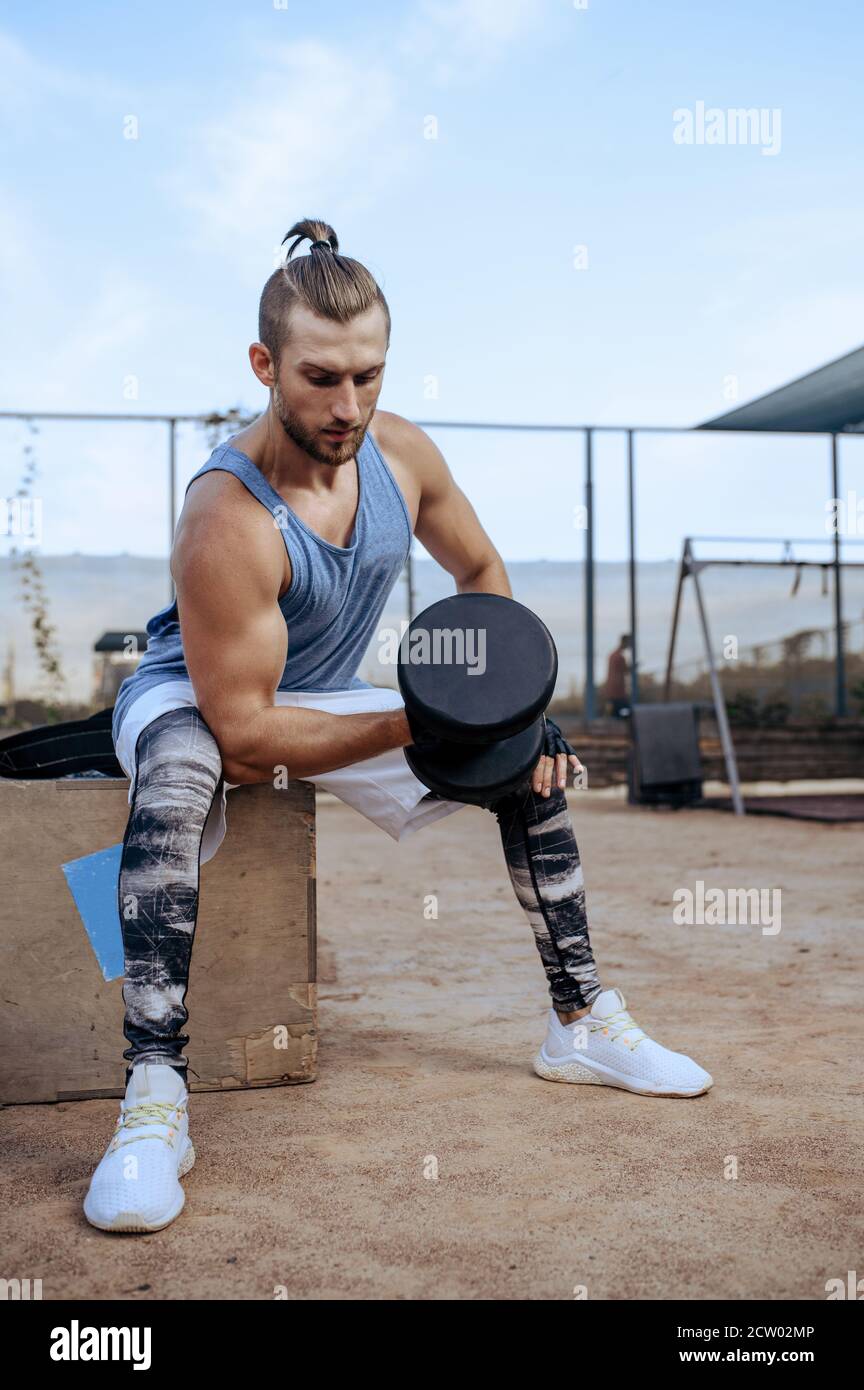 Man doing exercise with dumbbell, street workout Stock Photo - Alamy