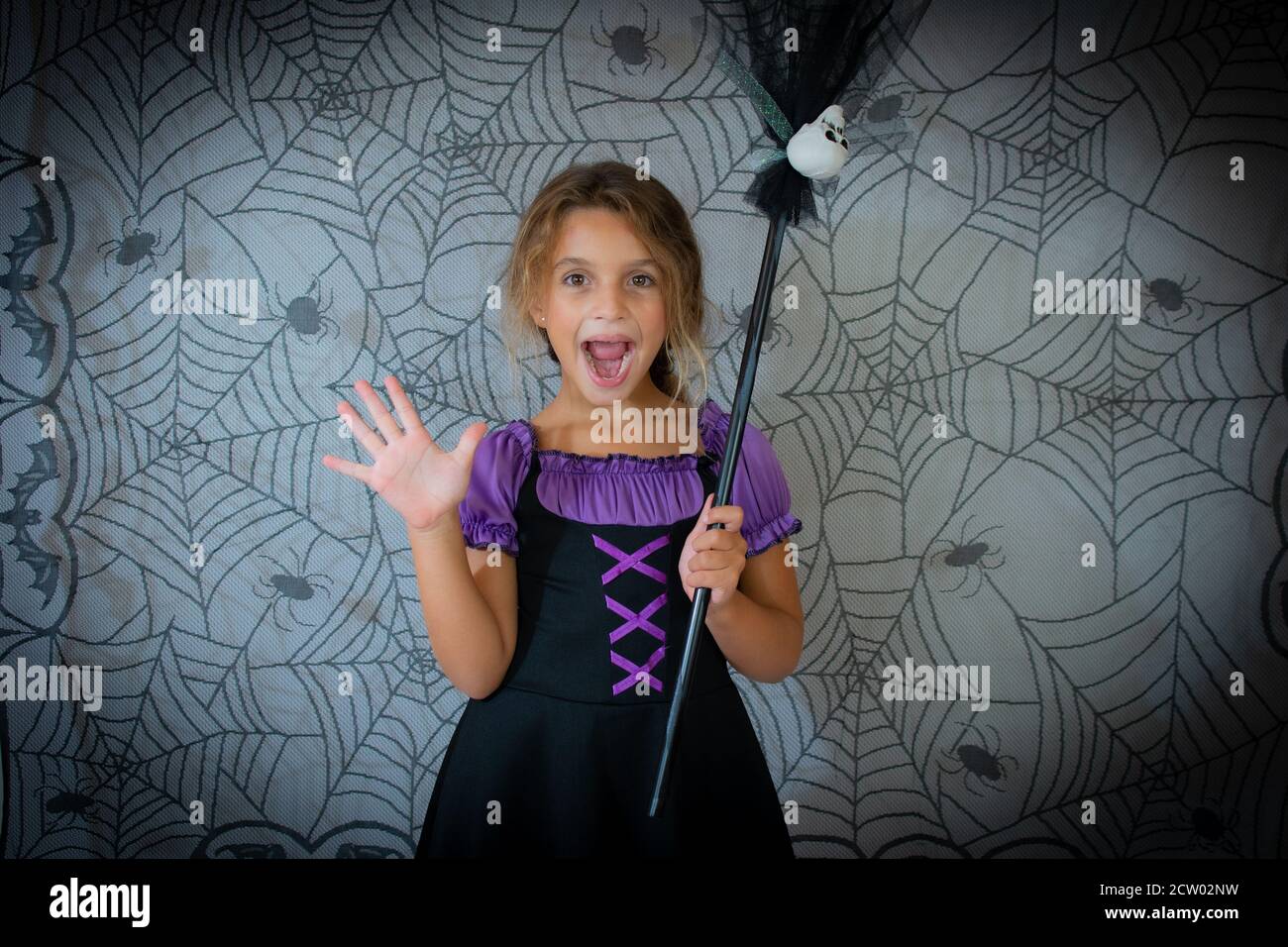 funny child girl in witch costume for Halloween over cobweb background ...