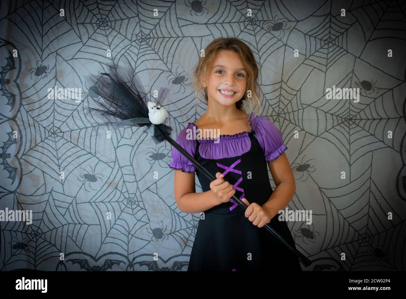 funny child girl in witch costume for Halloween over cobweb background ...