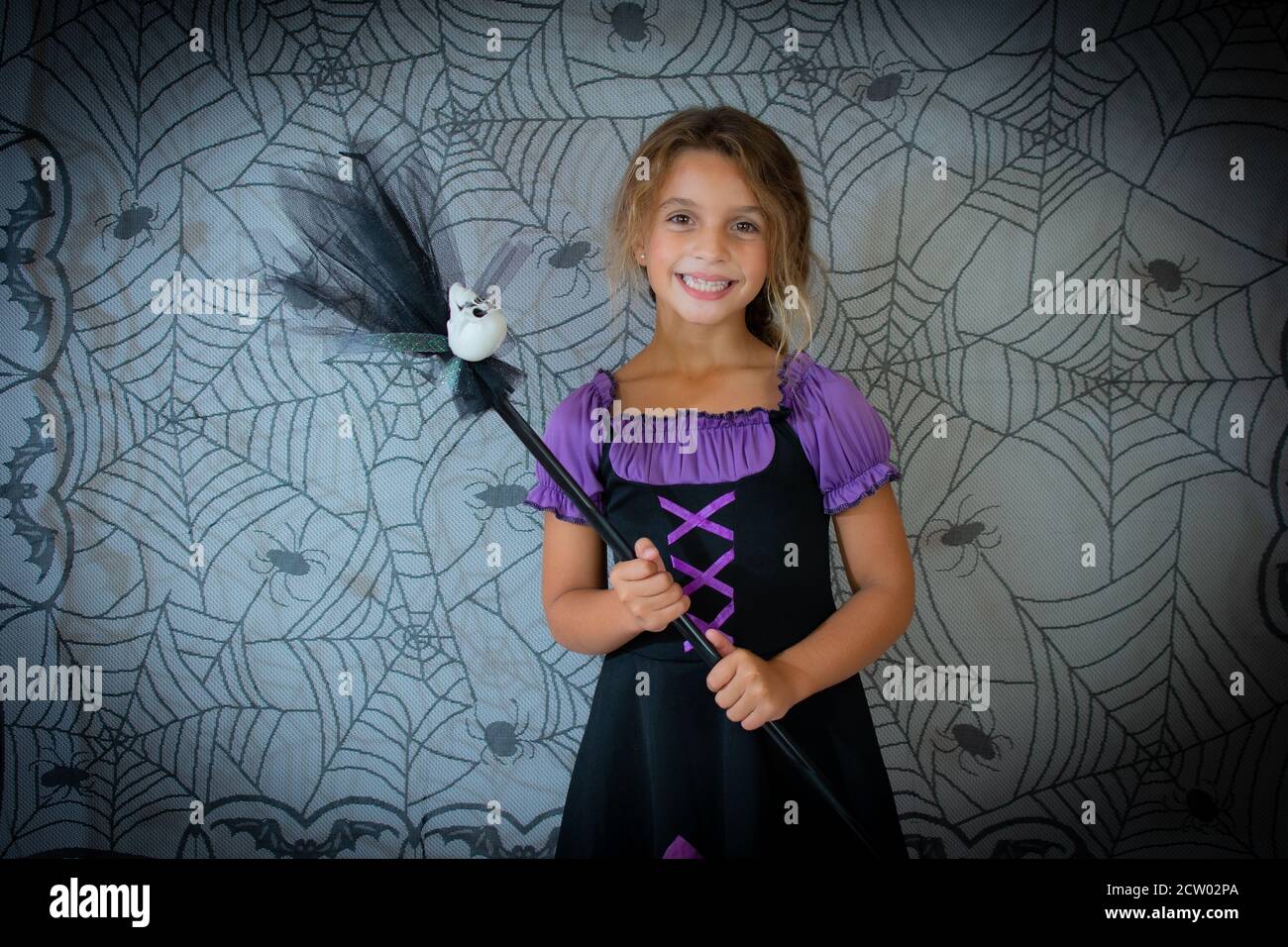 funny child girl in witch costume for Halloween over cobweb background ...
