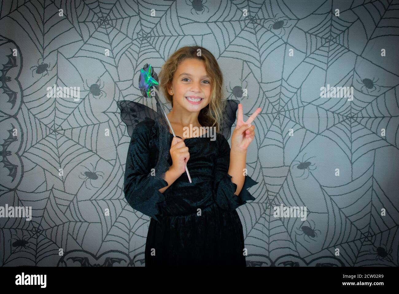 funny child girl in witch costume for Halloween over cobweb background ...