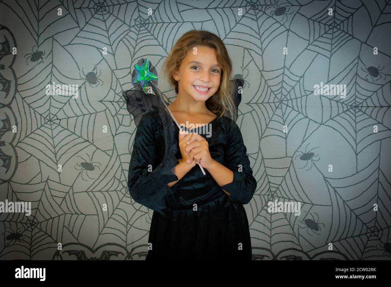 funny child girl in witch costume for Halloween over cobweb background ...
