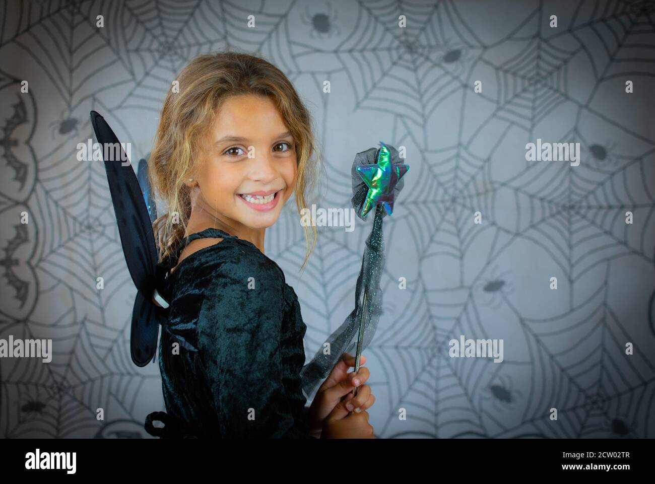 funny child girl in witch costume for Halloween over cobweb background ...
