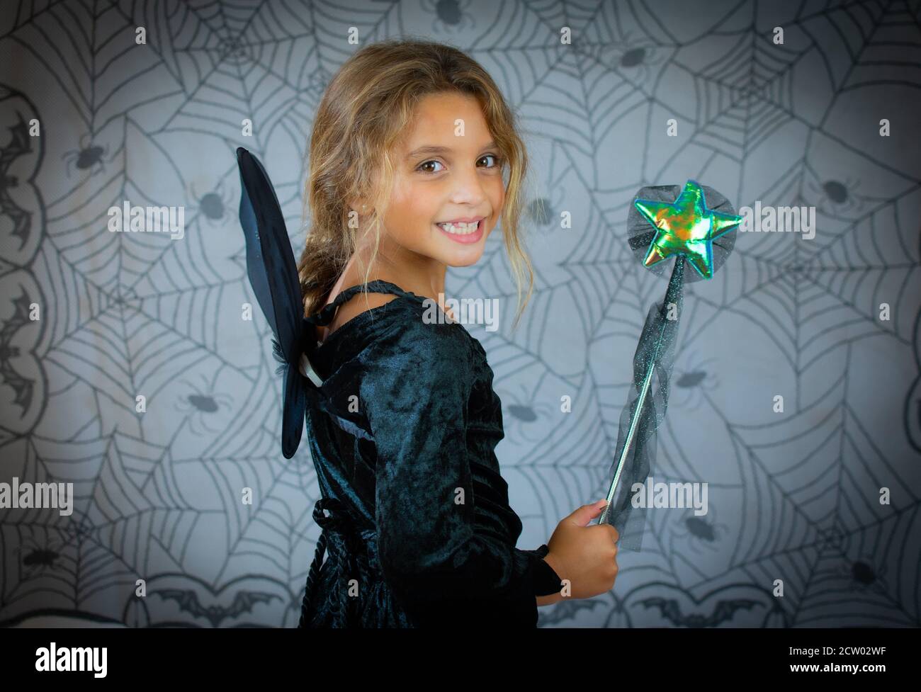 funny child girl in witch costume for Halloween over cobweb background ...