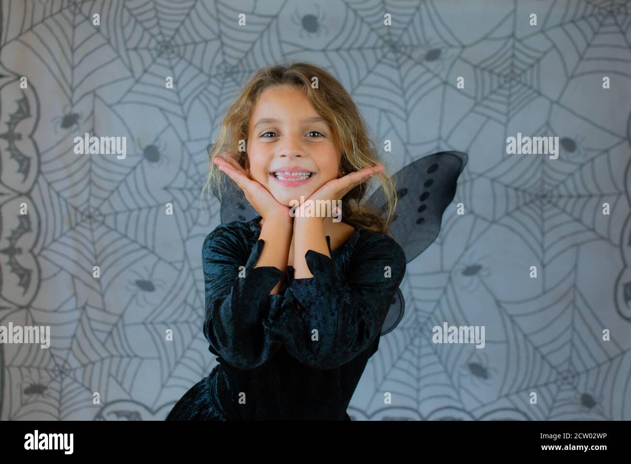 funny child girl in witch costume for Halloween over cobweb background ...
